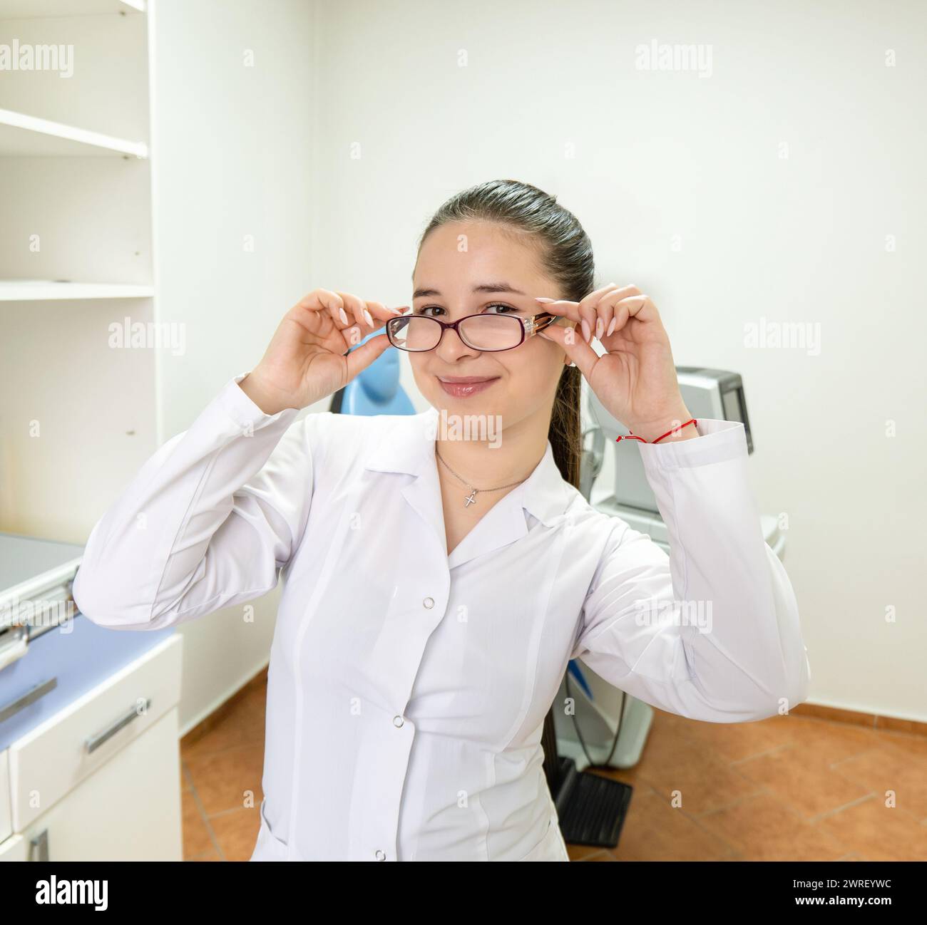 A woman in a white lab coat adjusts her glasses on her arm. Her vision ...