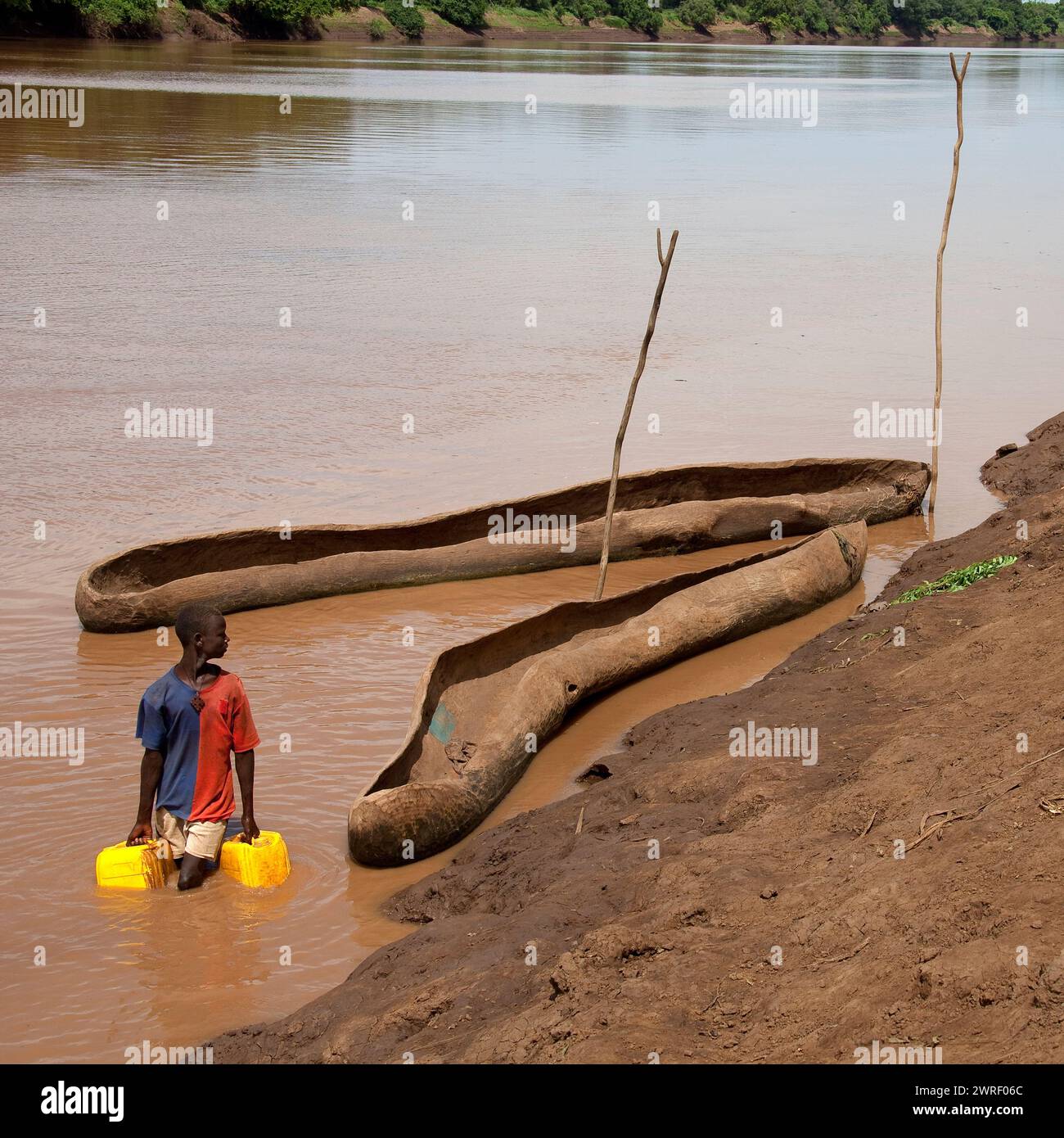 OMO VALLEY, ETHIOPIA - NOVEMBER 23, 2011: The man gathers water in ...