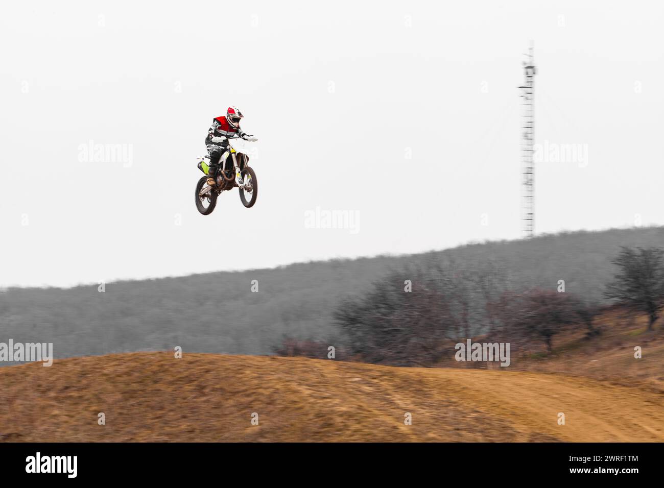 A person on a motorcycle is performing a jump on a dirt bike, with the ...