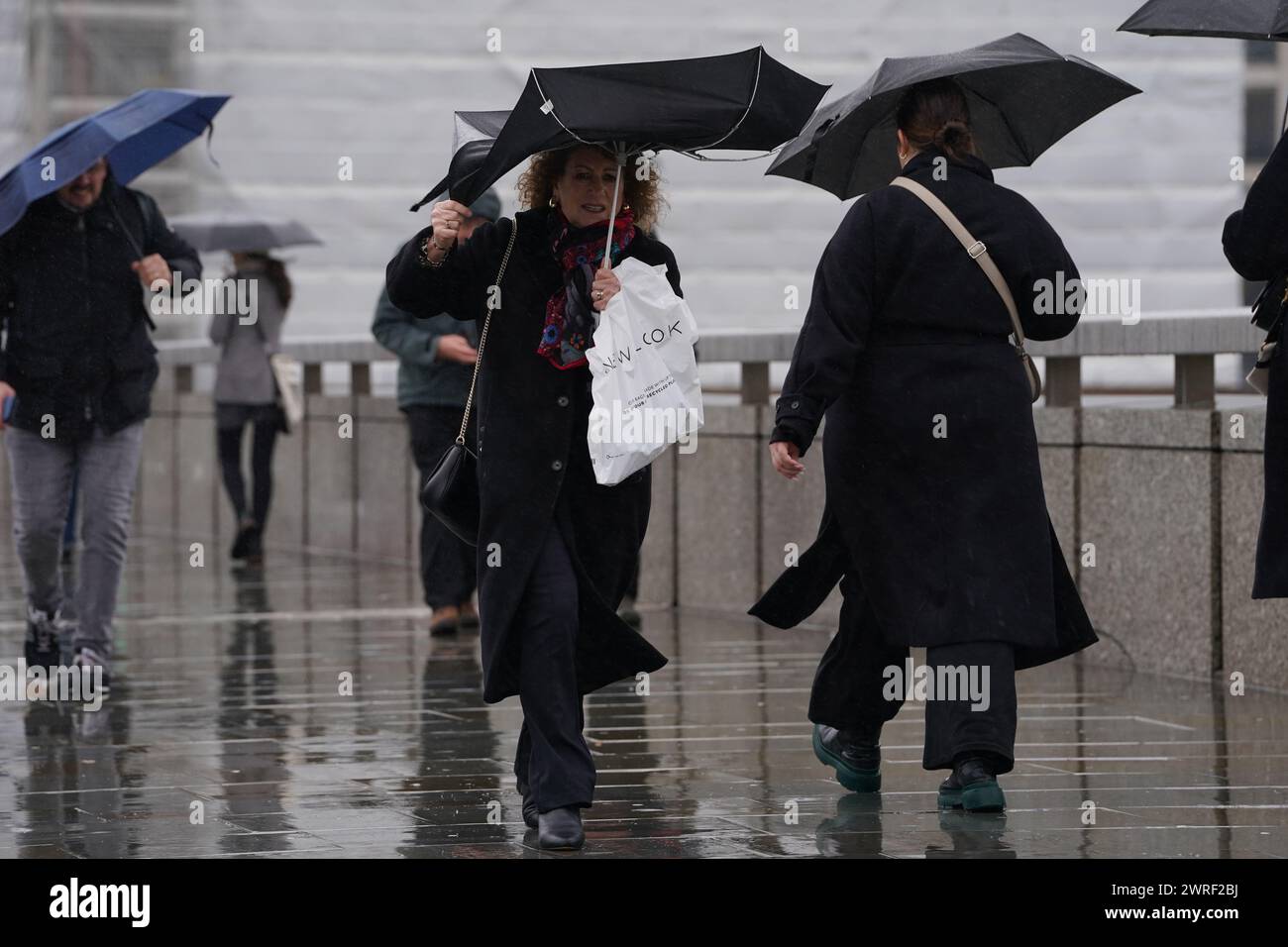 People walk in the rain over London Bridge in central London. Picture ...