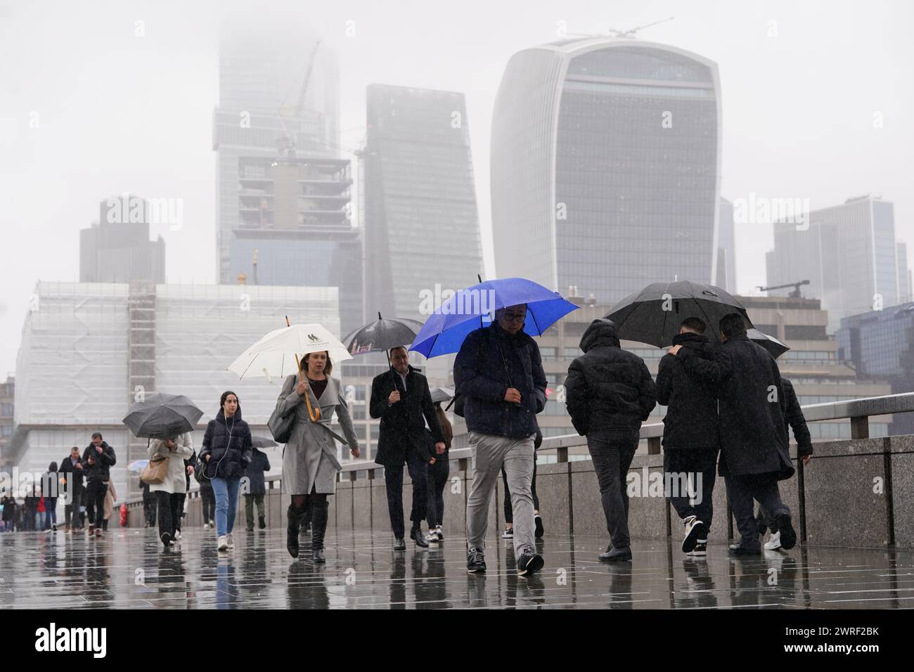 People walk in the rain over London Bridge in central London. Picture ...