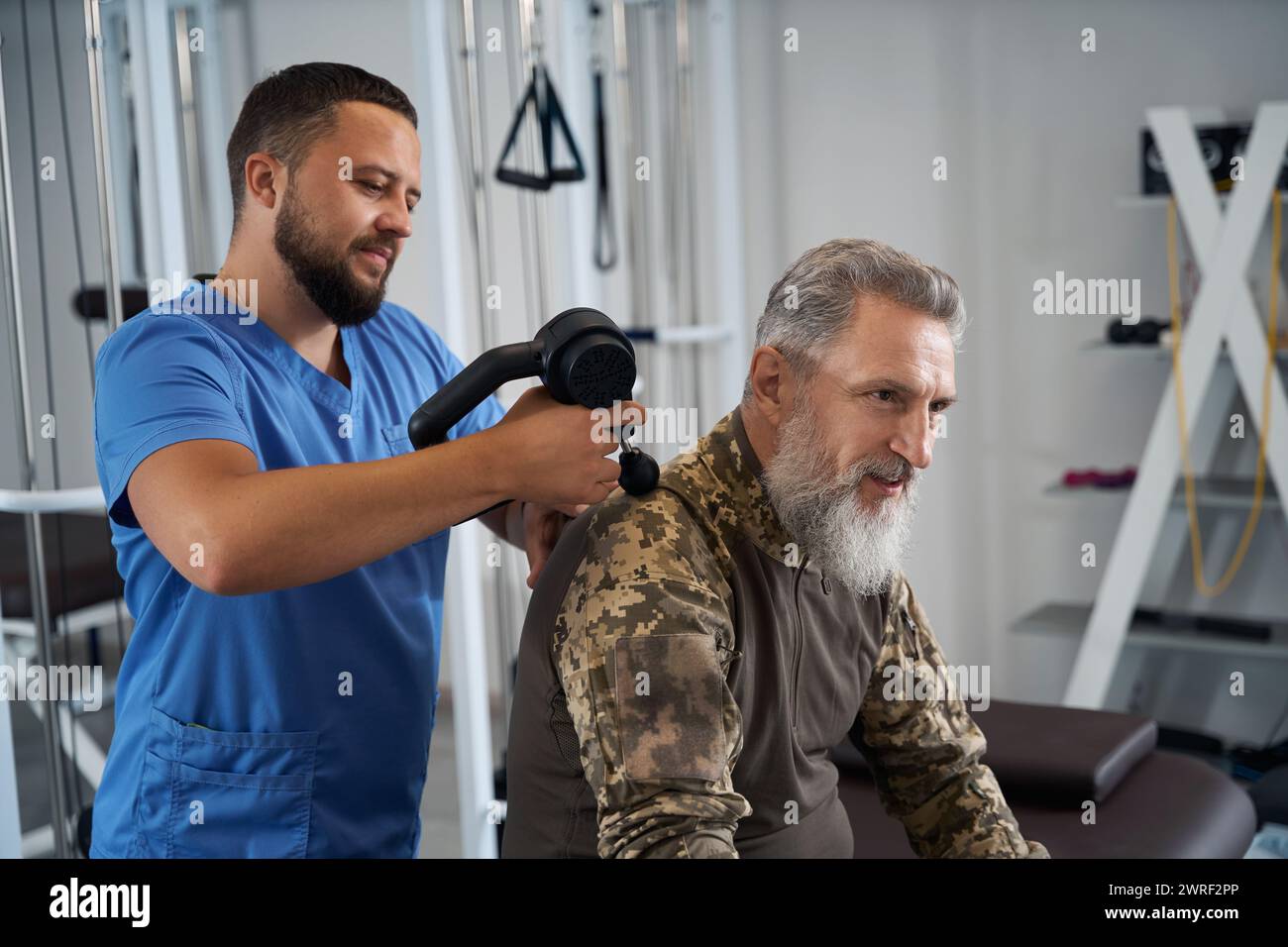 Physiotherapist performs a hardware massage on back of military man ...