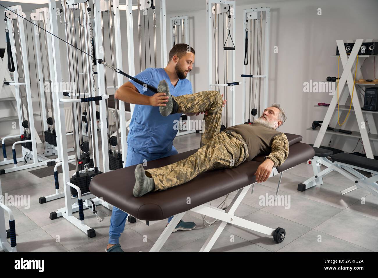 Military patient doing muscle stretching exercises in a rehabilitation ...