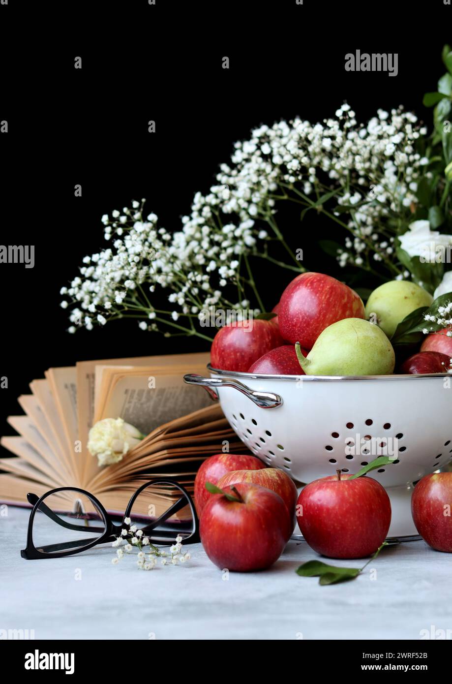 Shiny red apples, white Gypsophila flowers and open book on a table ...