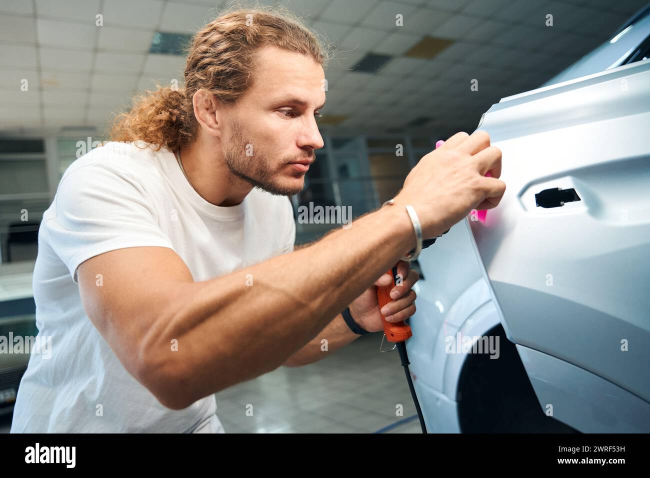 Guy uses an industrial dryer when detailing a car Stock Photo - Alamy