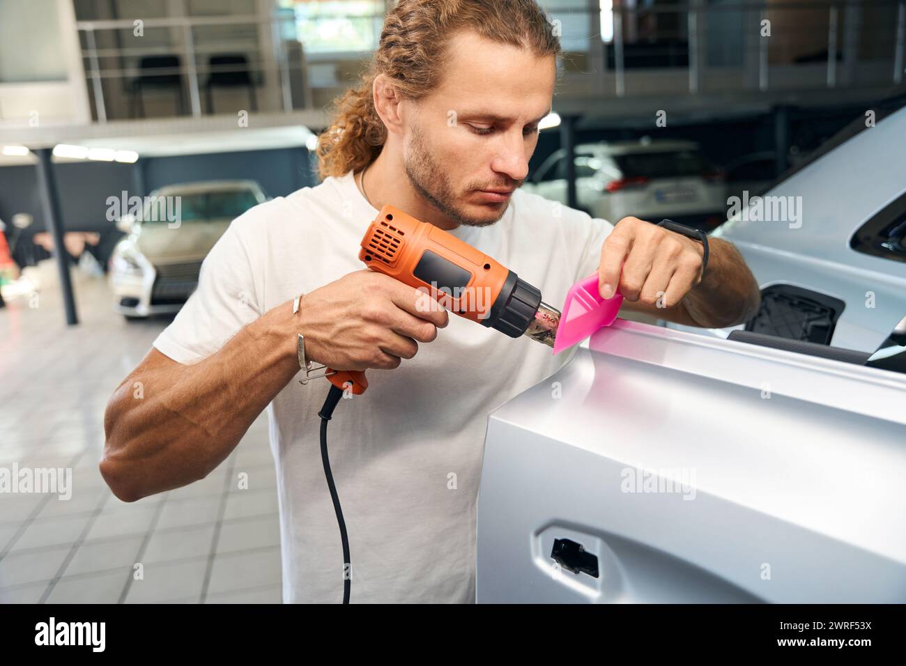 Male uses an industrial dryer when detailing cars Stock Photo - Alamy