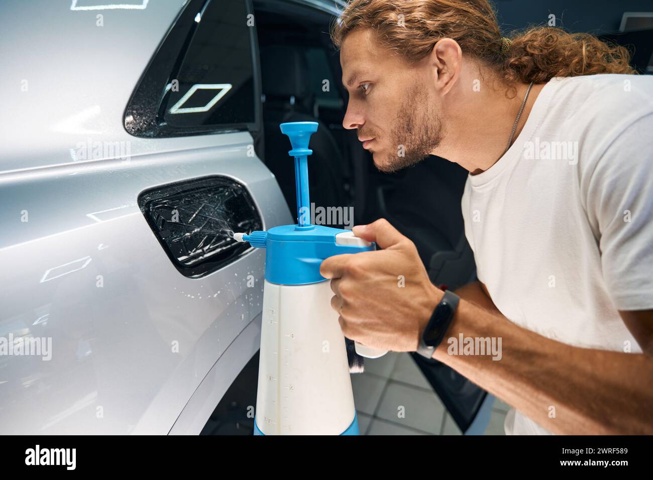 Master uses a spray bottle in process of car detailing Stock Photo - Alamy