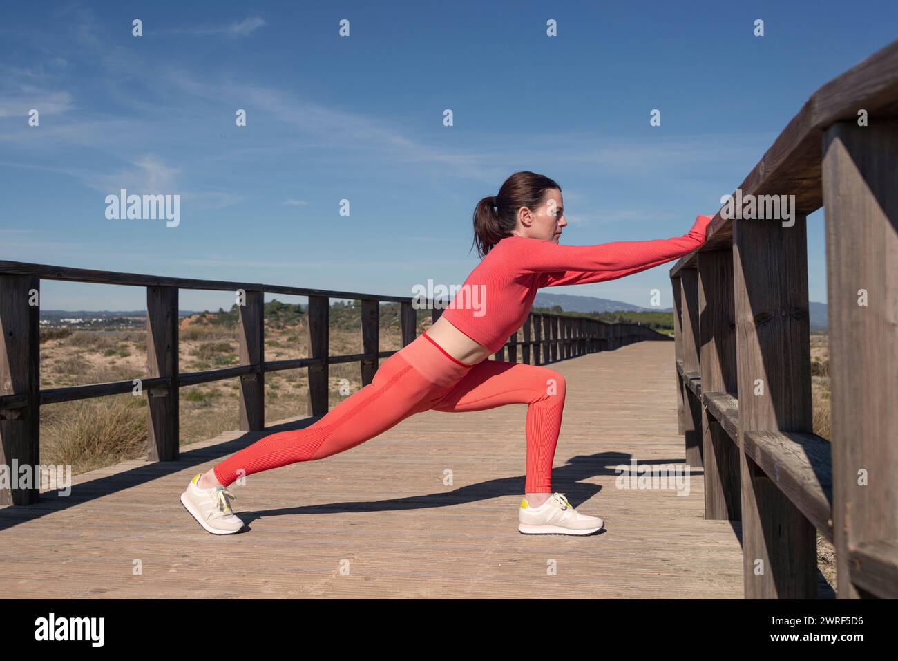 Sporty woman doing a leg stretch warm up exercise outside on a ...