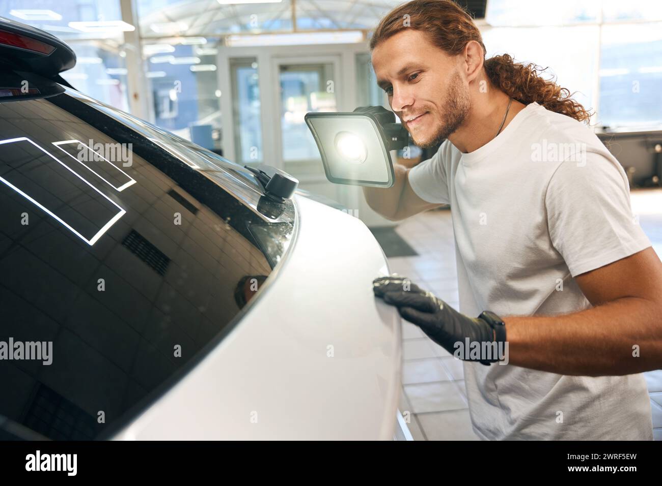 Long-haired man conducts a check inspection of a car body Stock Photo ...