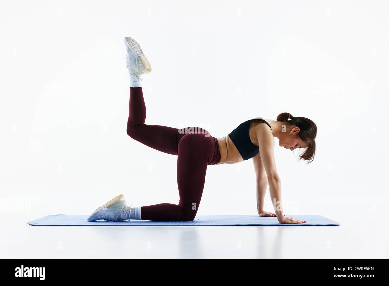 Sportive young woman in leggings and top training, standing on knees ...