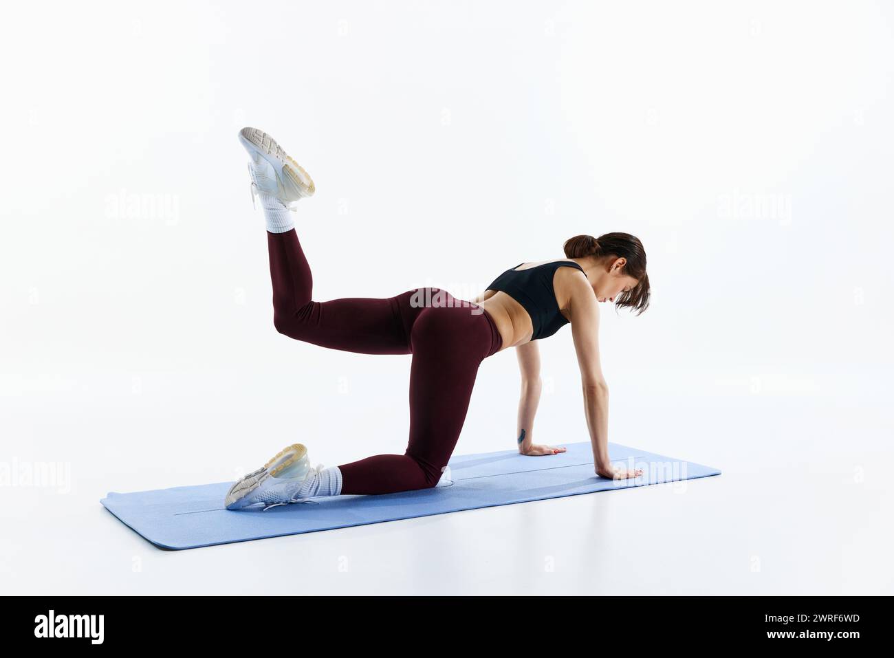 Young athletic woman in leggings and top training, standing on knees ...