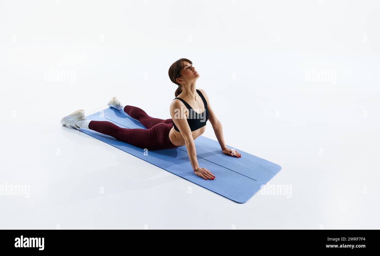 Young slim woman taking care after body condition, doing yoga exercises ...
