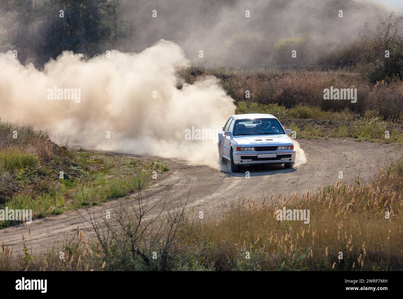 Sunny summer day. Dusty rally track. A rally car makes a lot of dust in ...