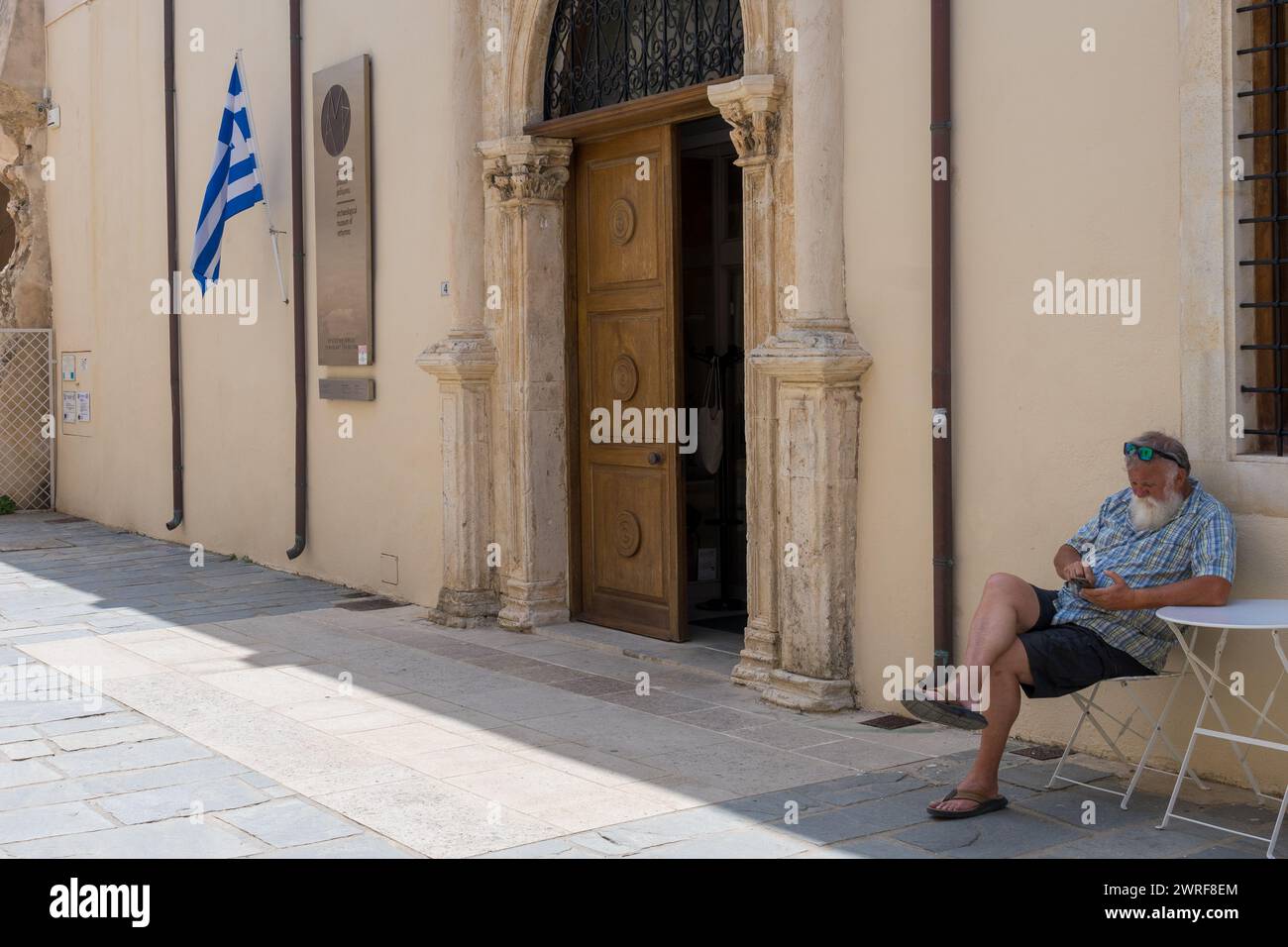 A typical street scene in Rethyymnon, Crete as a man sits outdide the ...