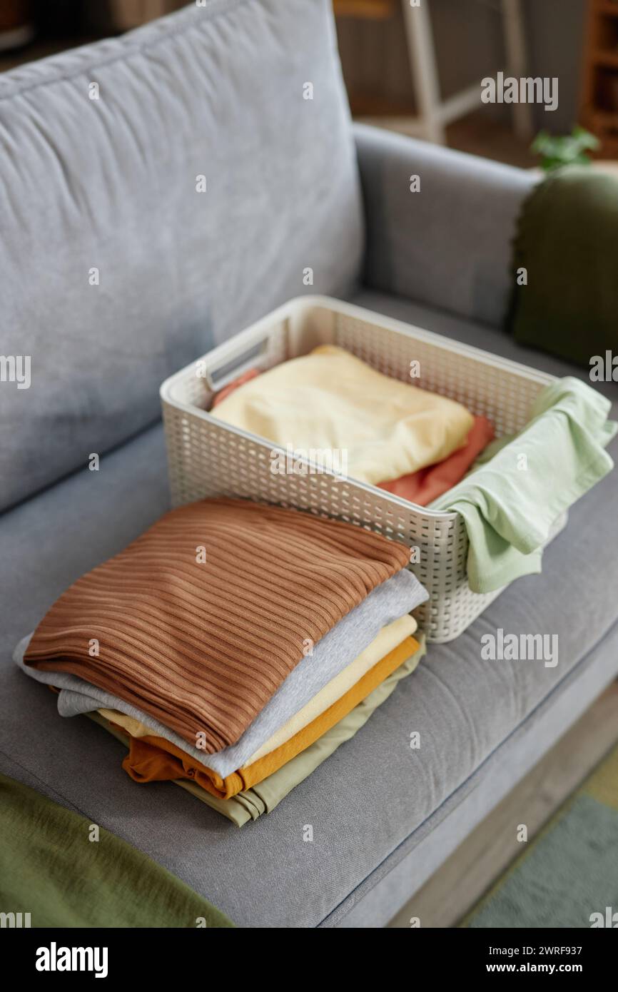 Vertical background image of clean clothes in stacks on couch in home ...