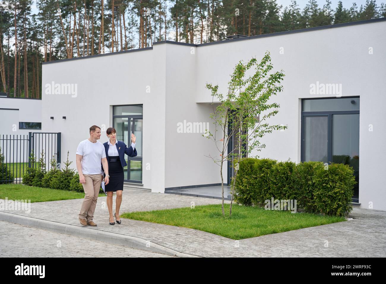 Buyer and sales manager walk through yard of new house Stock Photo - Alamy