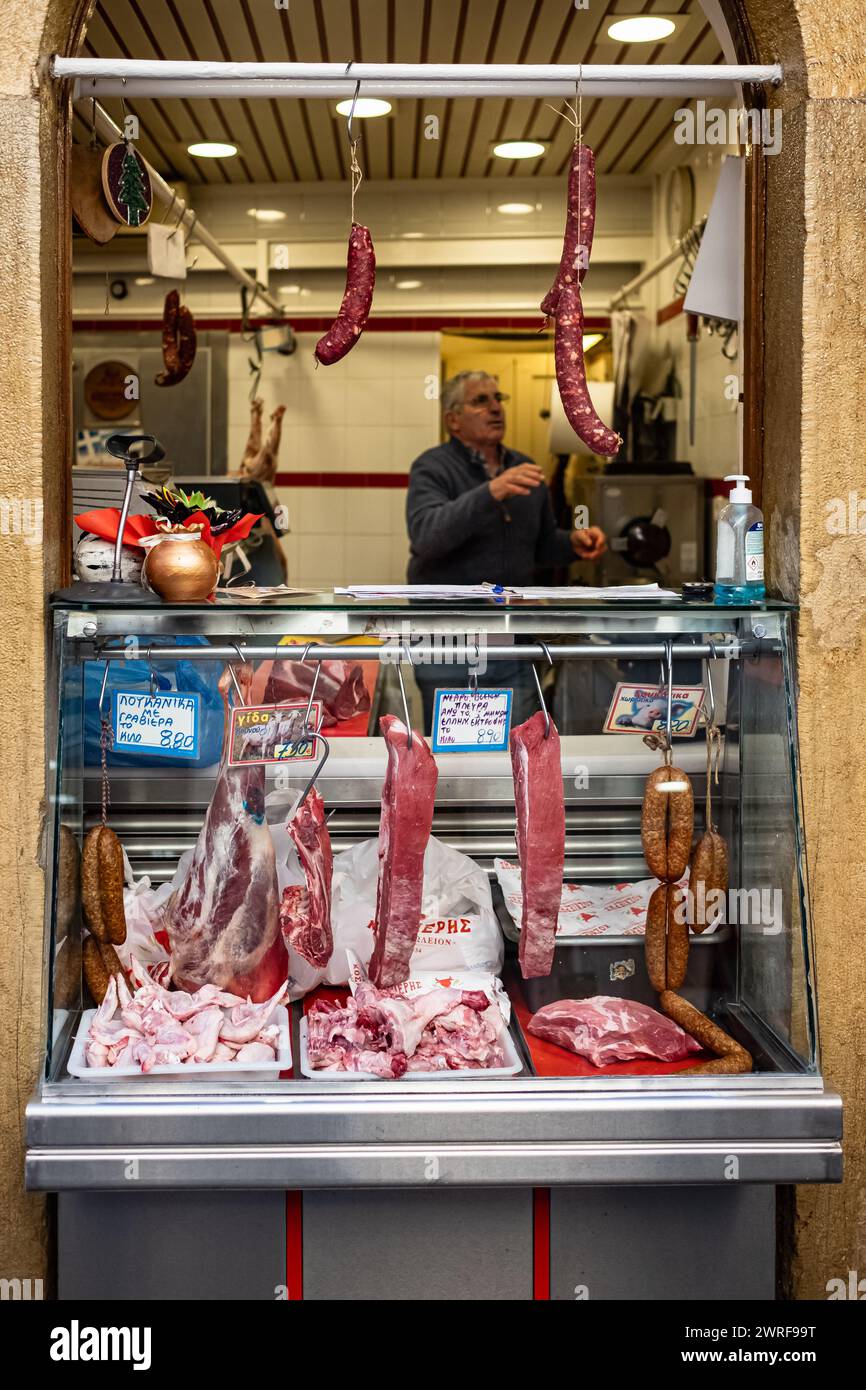 Saleswoman offering fresh meat at display in small street shop. Variety ...