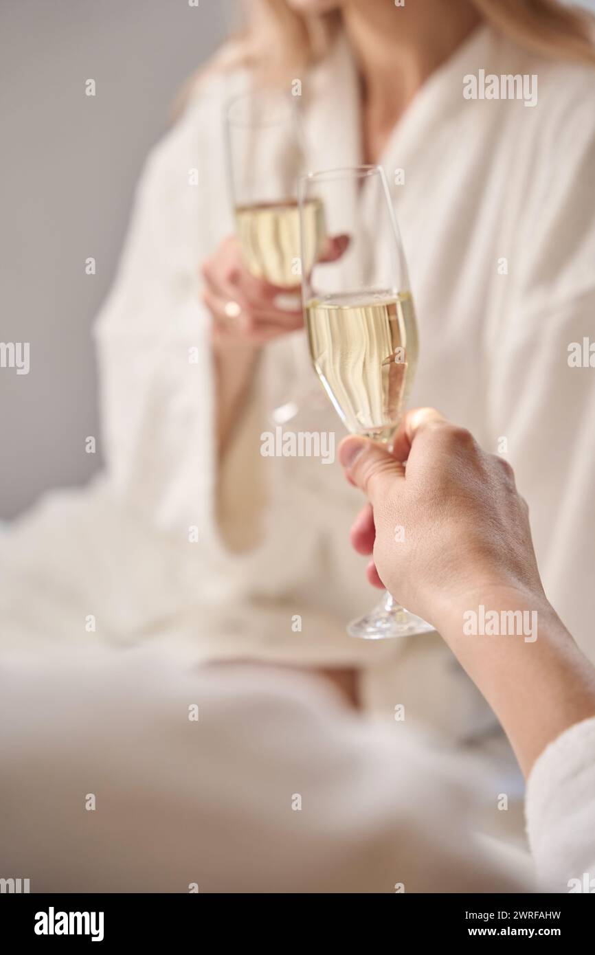 Romantic couple with a glass of champagne sat on large bed Stock Photo ...