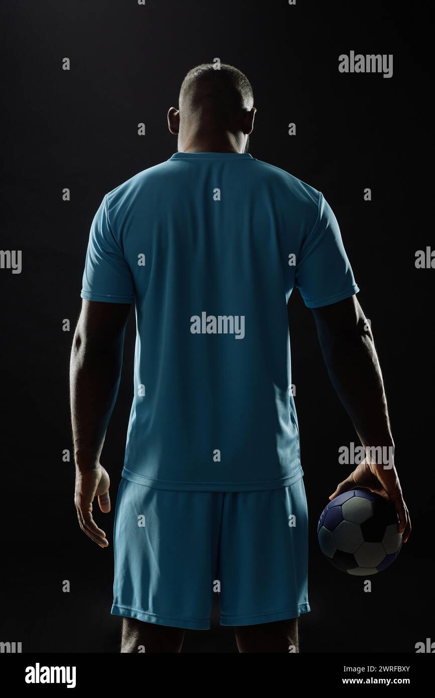 Dramatic back view of muscular football player standing against black ...