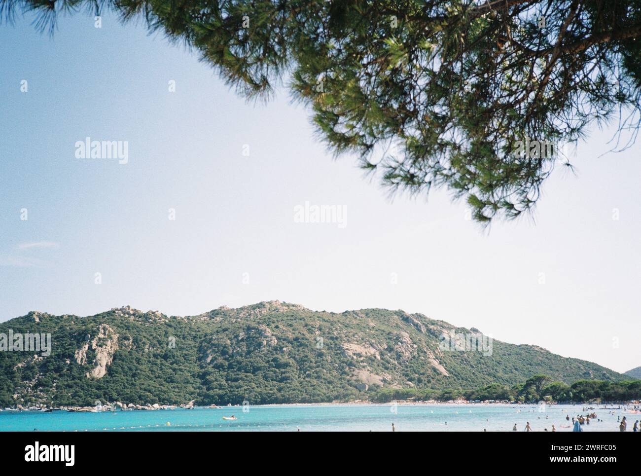 People basking in the sun on a sandy beach with crystal blue waters ...