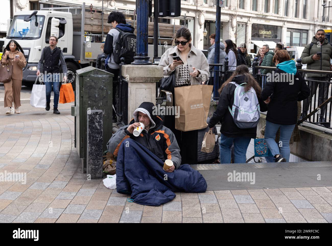 Shoppers ascend from the London Underground entrance occupied by ...