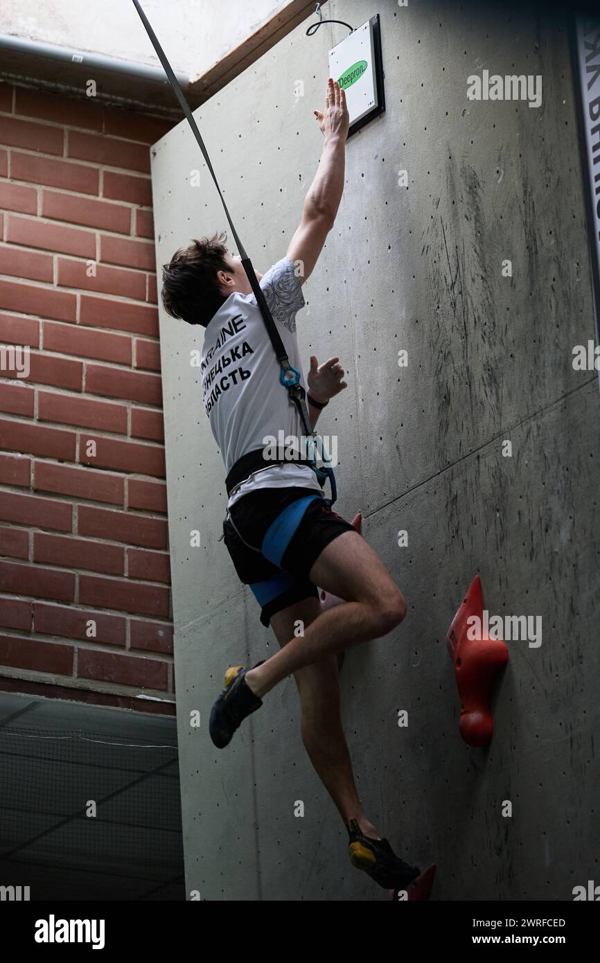 Climber press the button on the top of a climbing wall at indoor speed ...