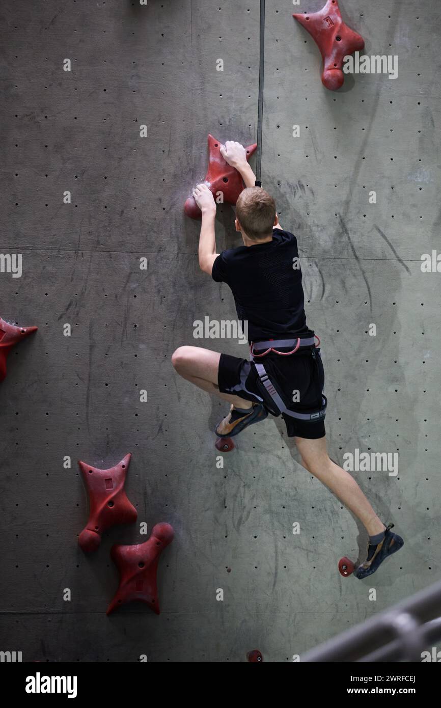 Young boy climbs the wall at indoor speed climbing competition. Kyiv ...