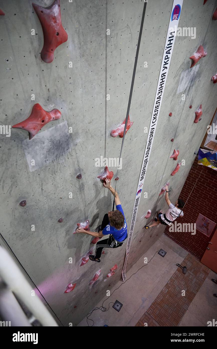 Boy climbs the vertical wall. Professional speed climbing competition ...