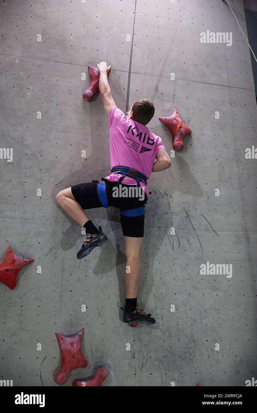 Young climber goes up the vertical wall wearing a safety harness at the ...