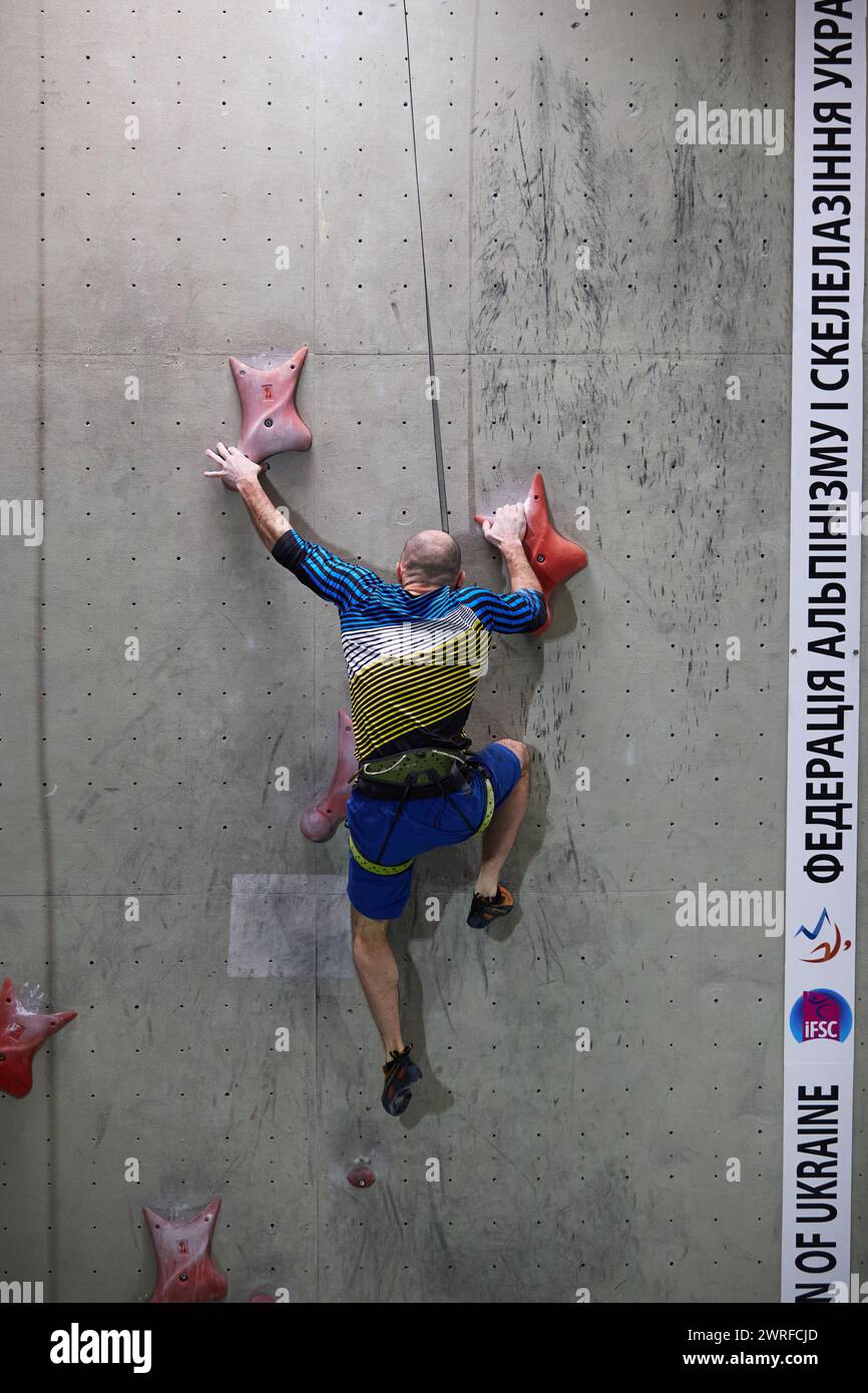 Male climber climbs up the vertical wall fast at speed climbing ...
