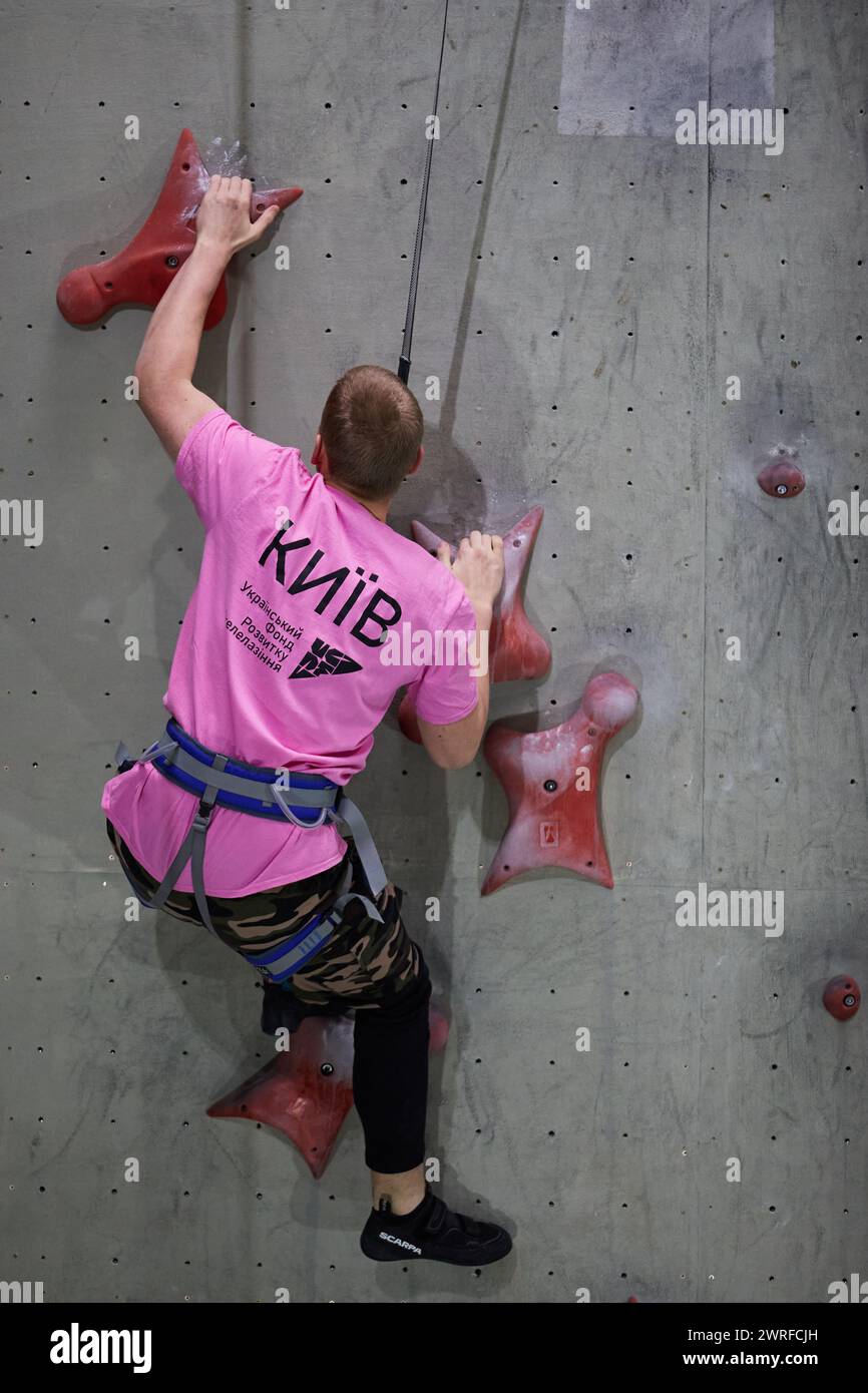 Young climber wearing a safety rope climbs up the wall at a speed ...