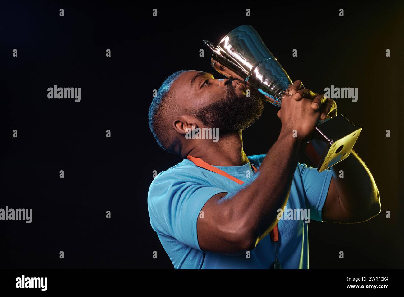 Side view portrait of muscular male sportsman kissing trophy cup and ...