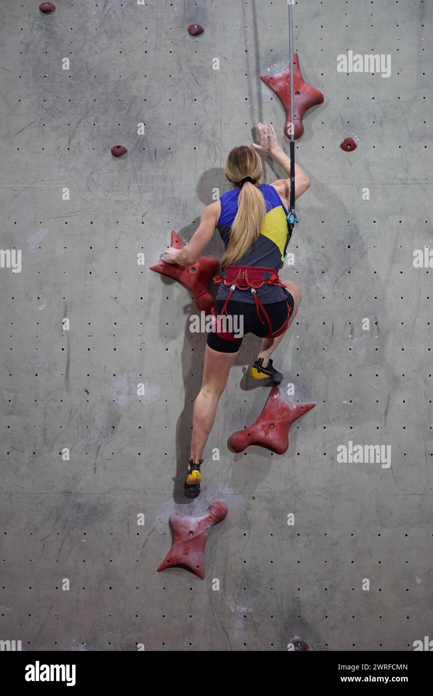 Professional female climber climbing up the vertical wall at the All ...