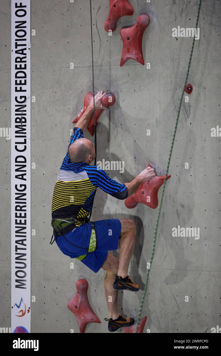 Professional speed climber wearing a safety rope climbs up the vertical ...