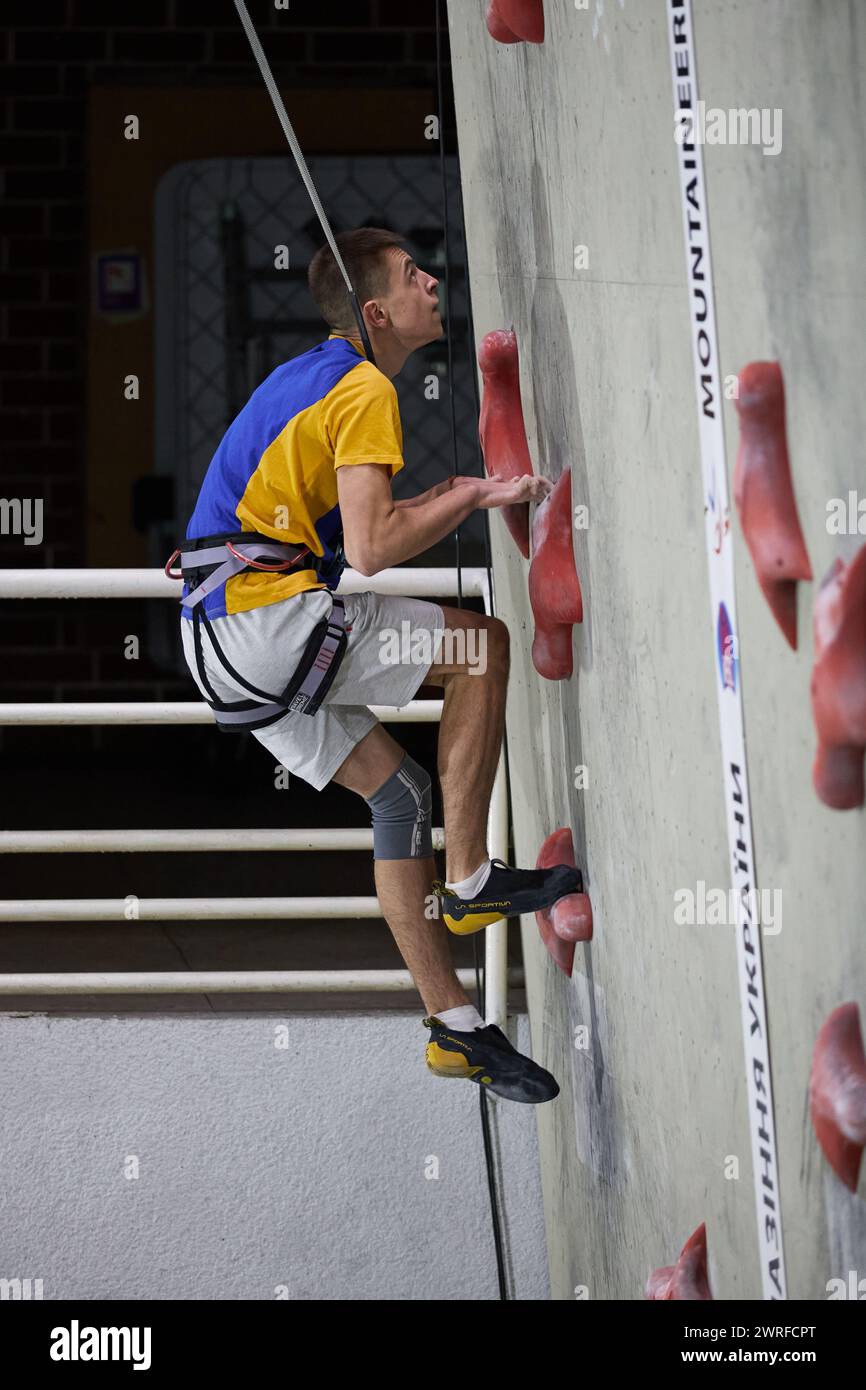Young speed climber climbs up the vertical wall at a professional ...