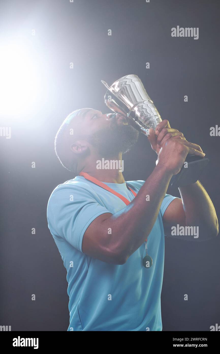 Vertical portrait of sportsman kissing trophy cup and celebrating ...