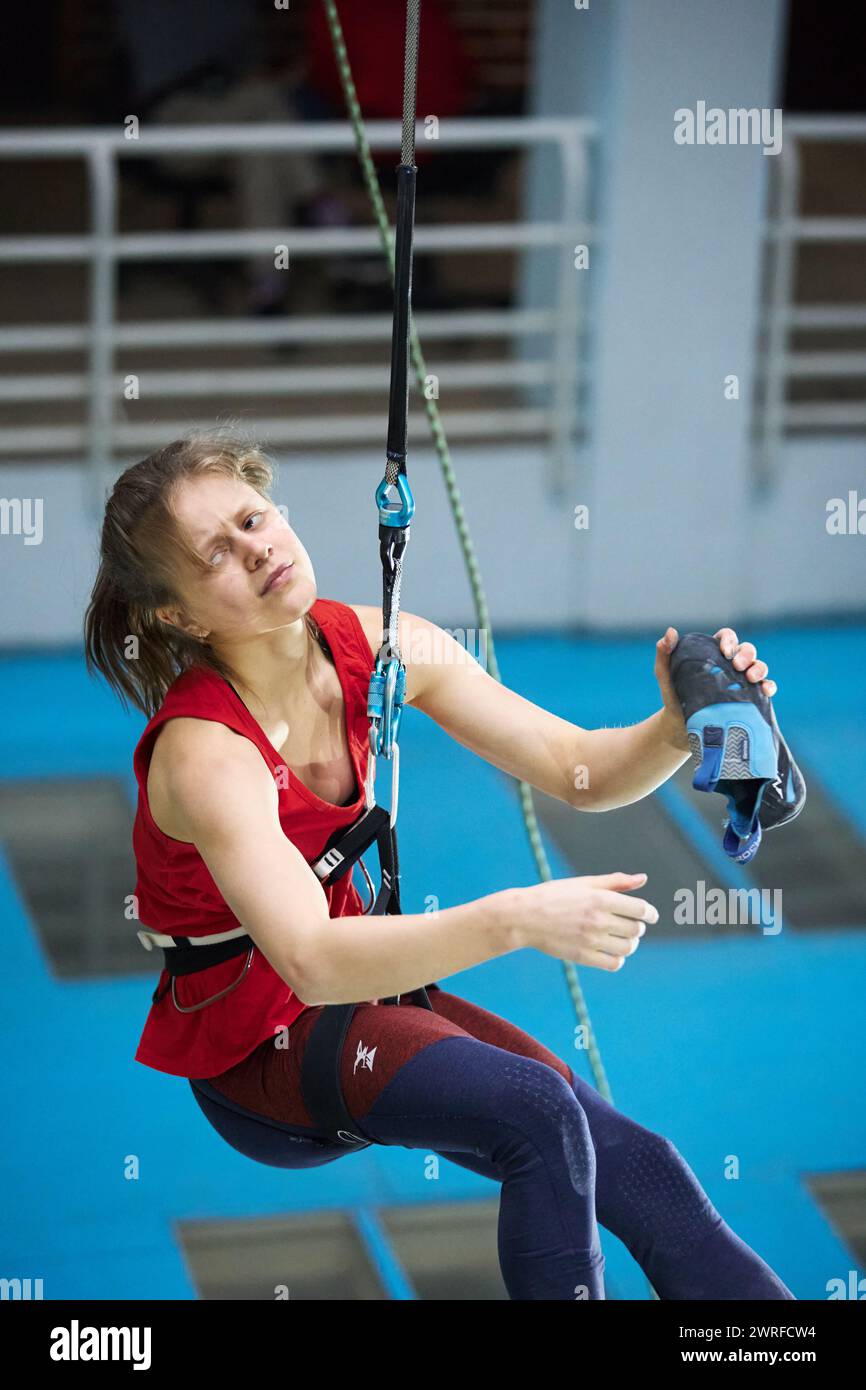 Unhappy young girl hanging on a safety harness after the fall at a ...