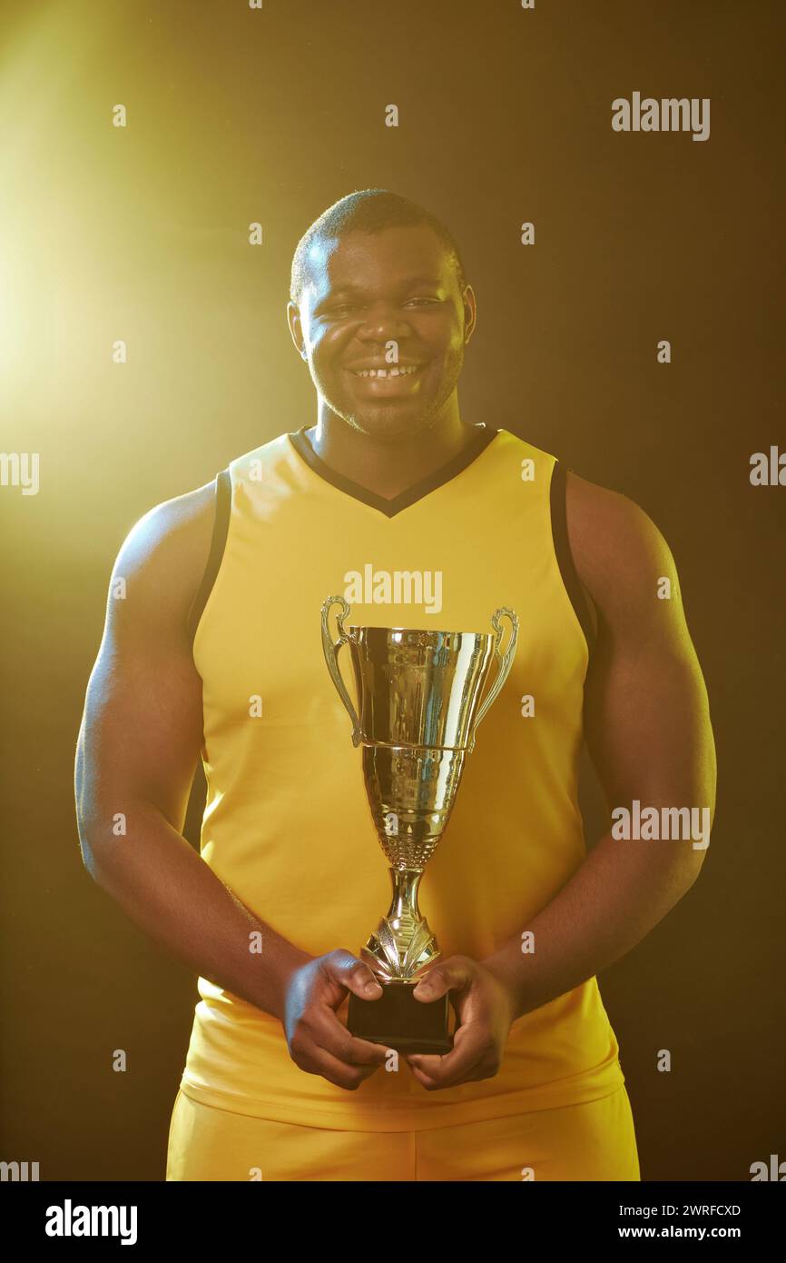 Vertical portrait of muscular sportsman holding trophy cup and smiling ...