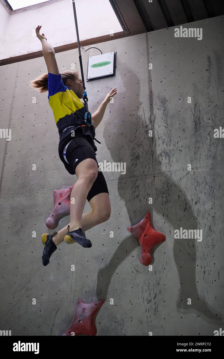 Young female climber hits the button at the top of a wall at a speed ...