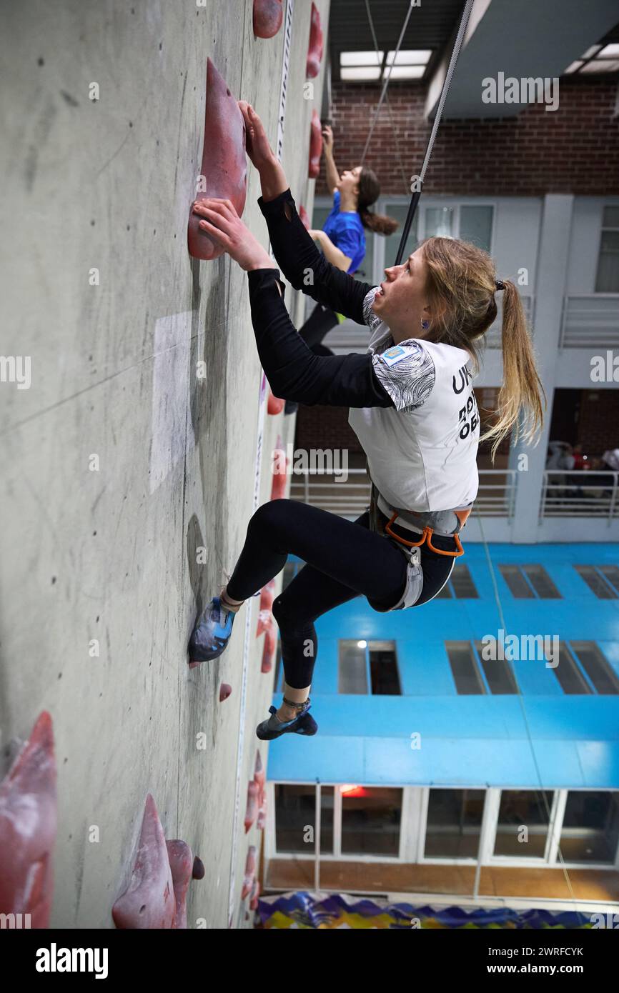 Young female climber climbs to the top of the speed wall at indoor ...
