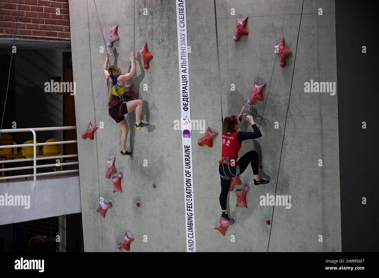 Young female climbers climb the vertical wall fast at a speed climbing ...