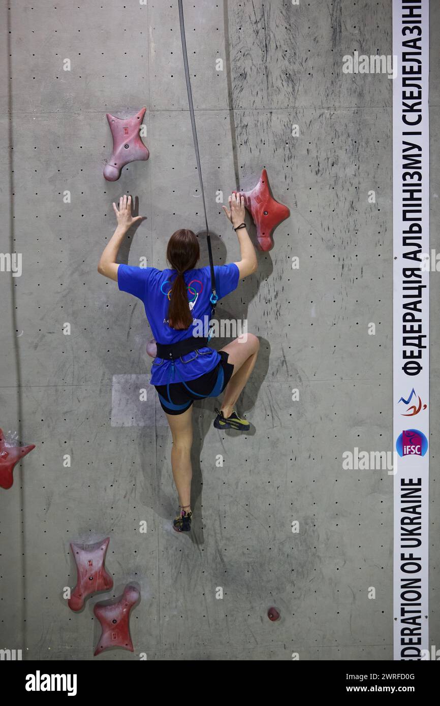 Female climber climbs on a vertical speed wall fast at a indoor speed ...