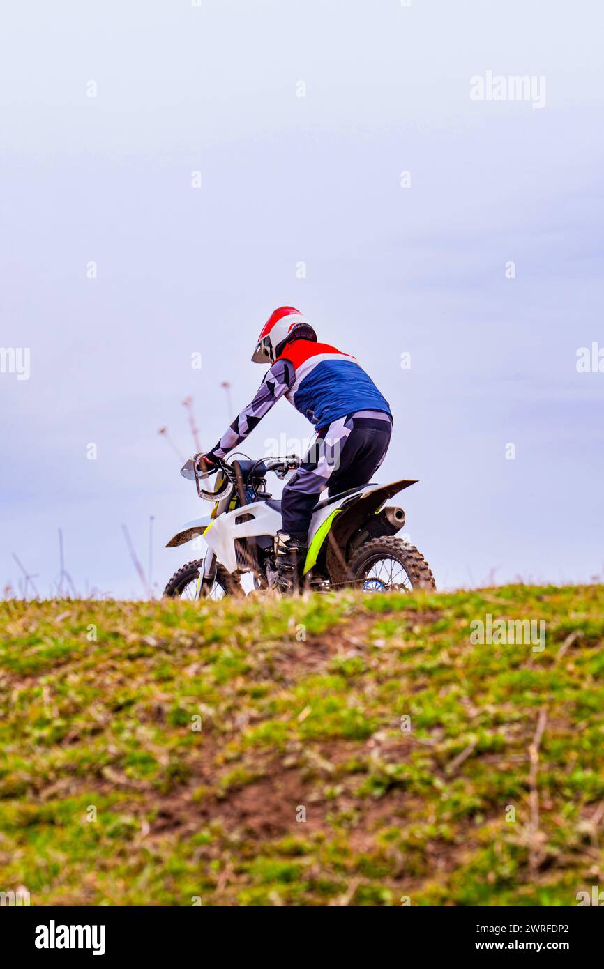 Riding a dirt bike downhill on a grassy slope. Helmet and motocross ...