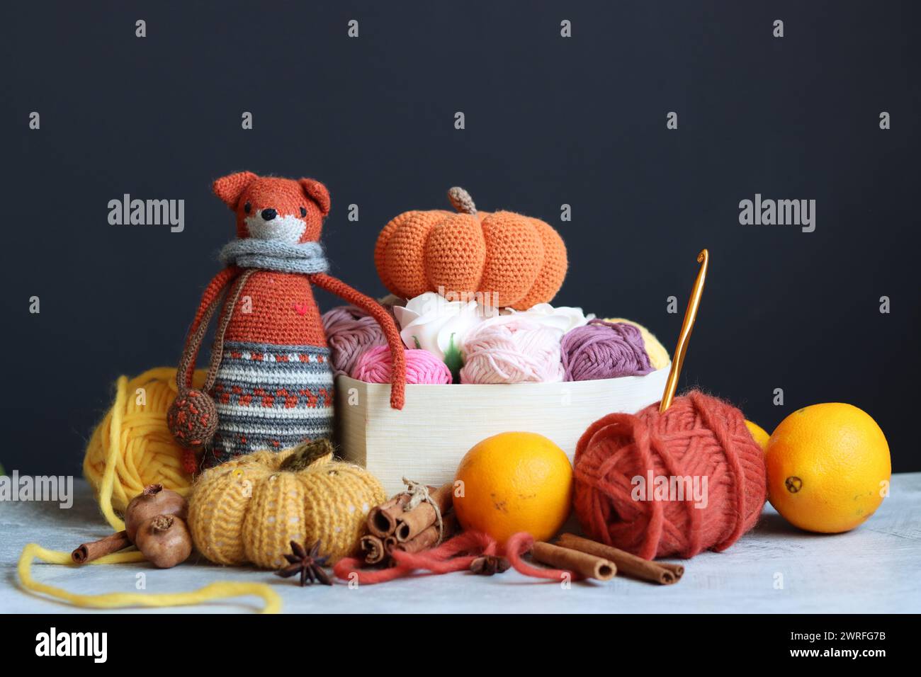 Knitted toys, yarn balls and autumn decorations on textured background ...