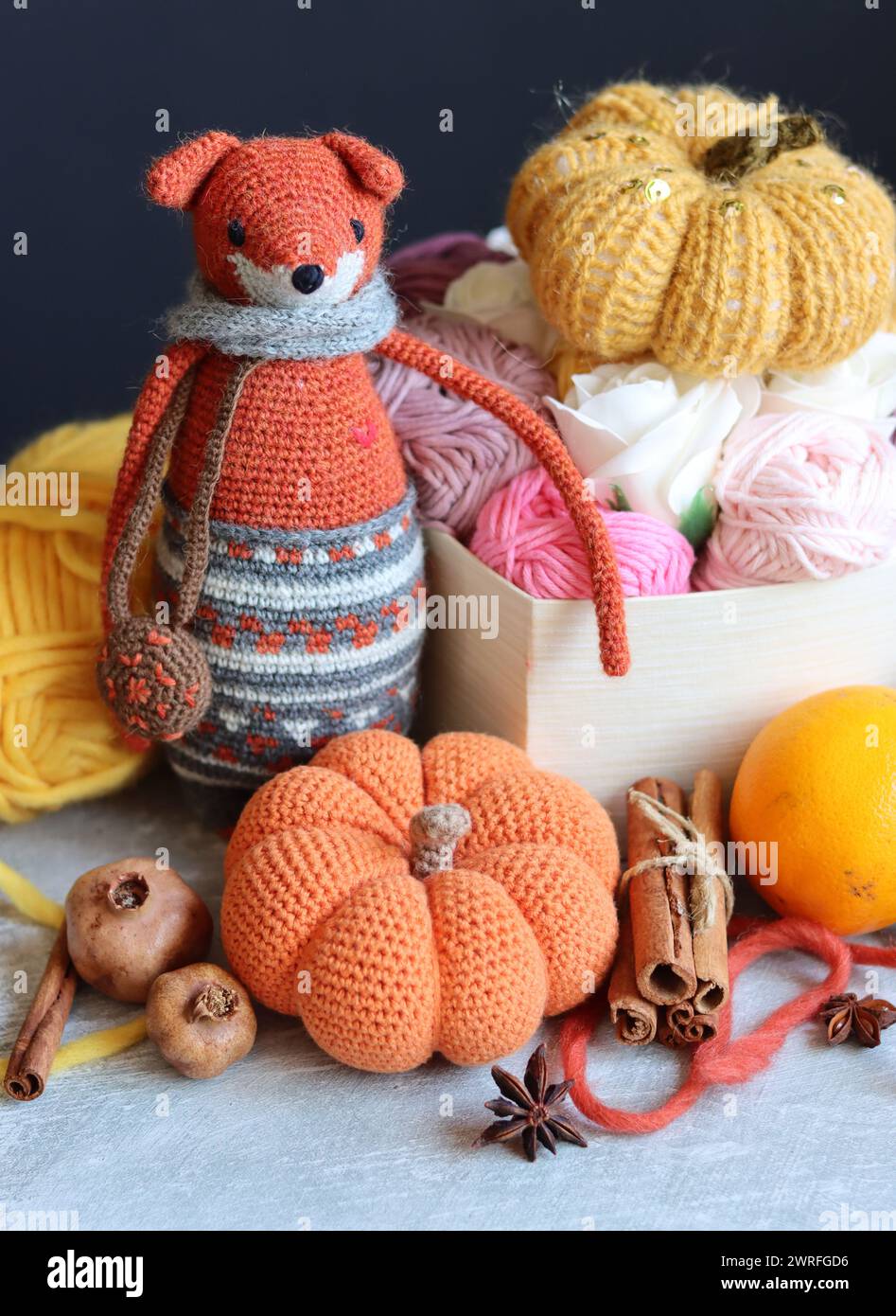 Knitted toy fox, yarn balls and autumn decorations on textured ...