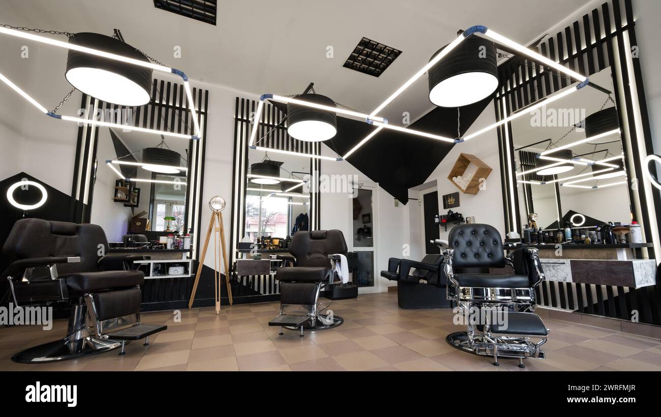 The modern interior of a men's barbershop with chairs is shot at a wide ...
