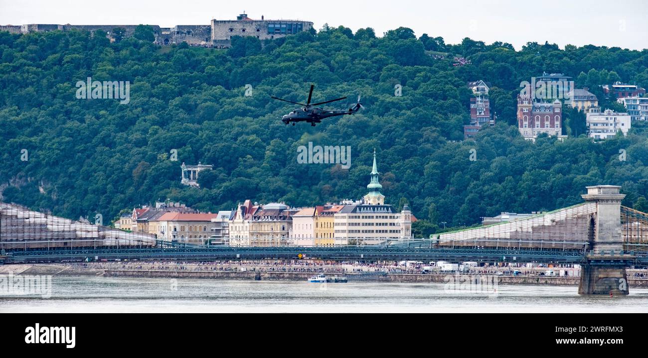Helicopter flying over the Danube river near a bridge with a cityscape ...