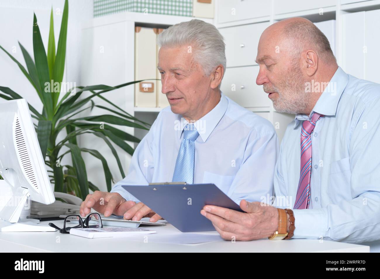 Two old business men sitting at desk and working Stock Photo - Alamy