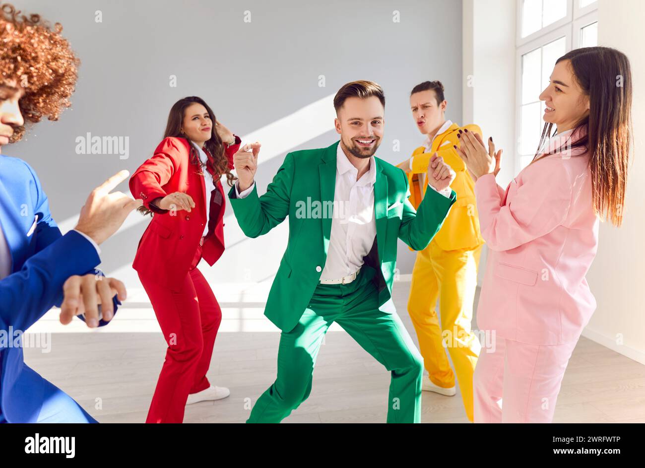 Group of cheerful friends in colorful suits having a party, dancing and ...