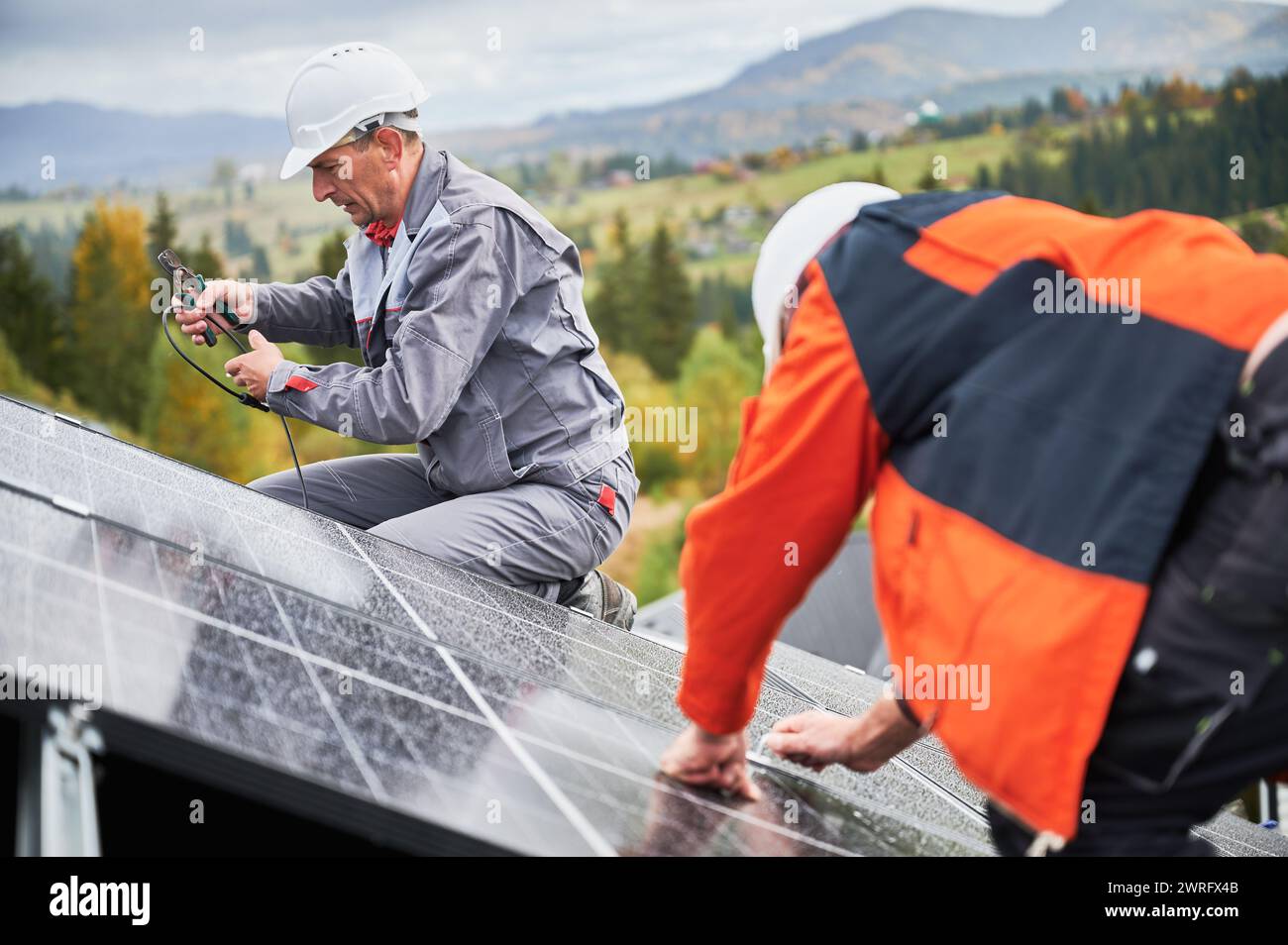 Installers connecting cables while installing photovoltaic solar panels ...